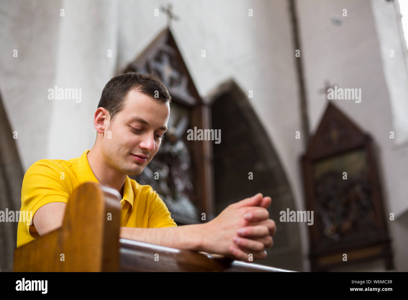 Handsome young man praying in a church Stock Photo - Alamy