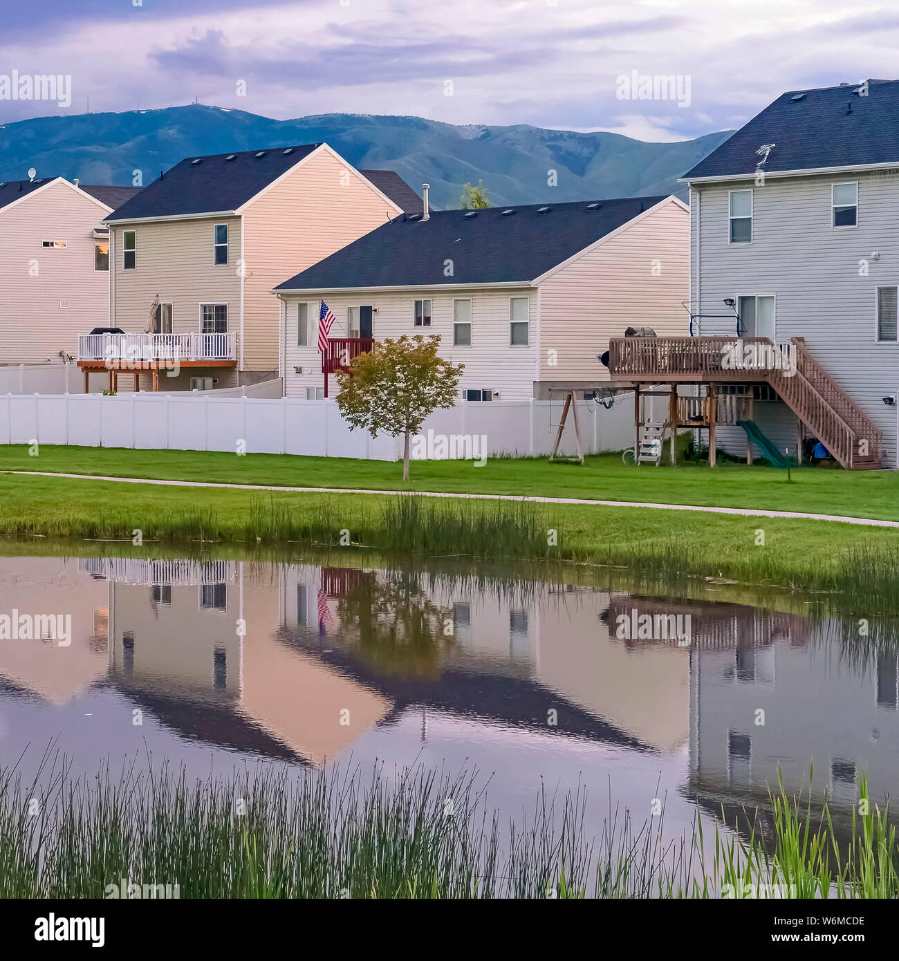 Square Shiny pond and pathway amid a grassy terrain in front of homes ...