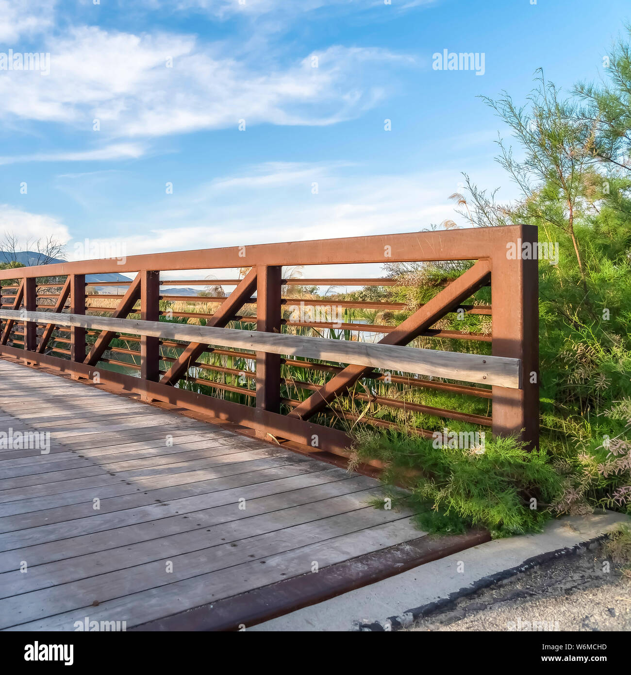 Square Sunny day view of a bridge with wooden deck and metal guardrail ...