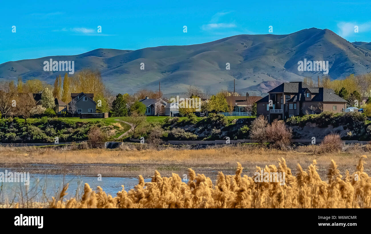 Panorama frame Lakefront houses with towering mountain and blue sky ...
