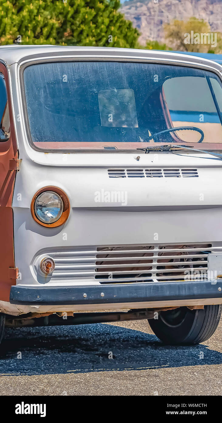 Vertical frame Front view of an old white van with brown door parked on ...