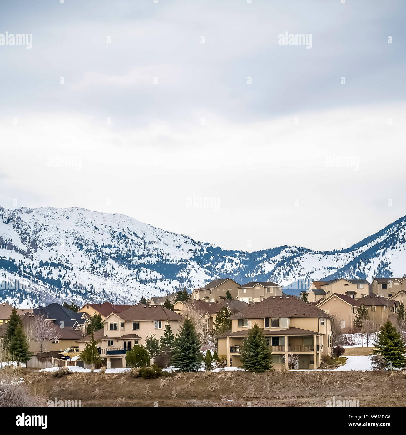 Square Paved road curving through snowy hill with multi storey homes in ...