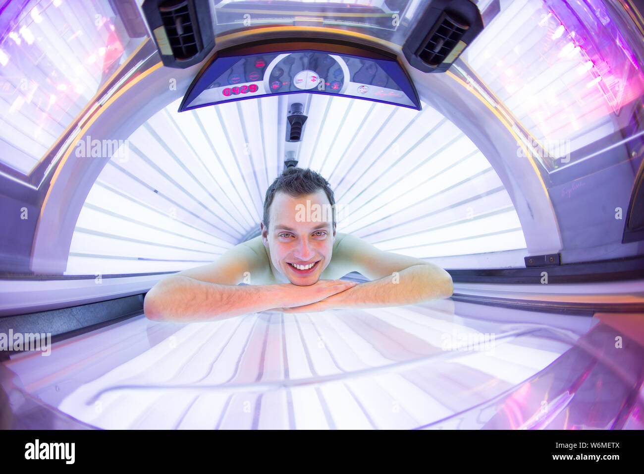 Handsome young man relaxing during a tanning session in a modern ...