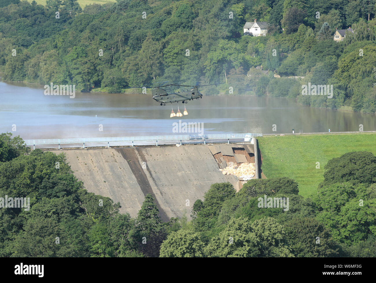 An RAF Chinook helicopter flies in sandbags to help repair the dam at ...