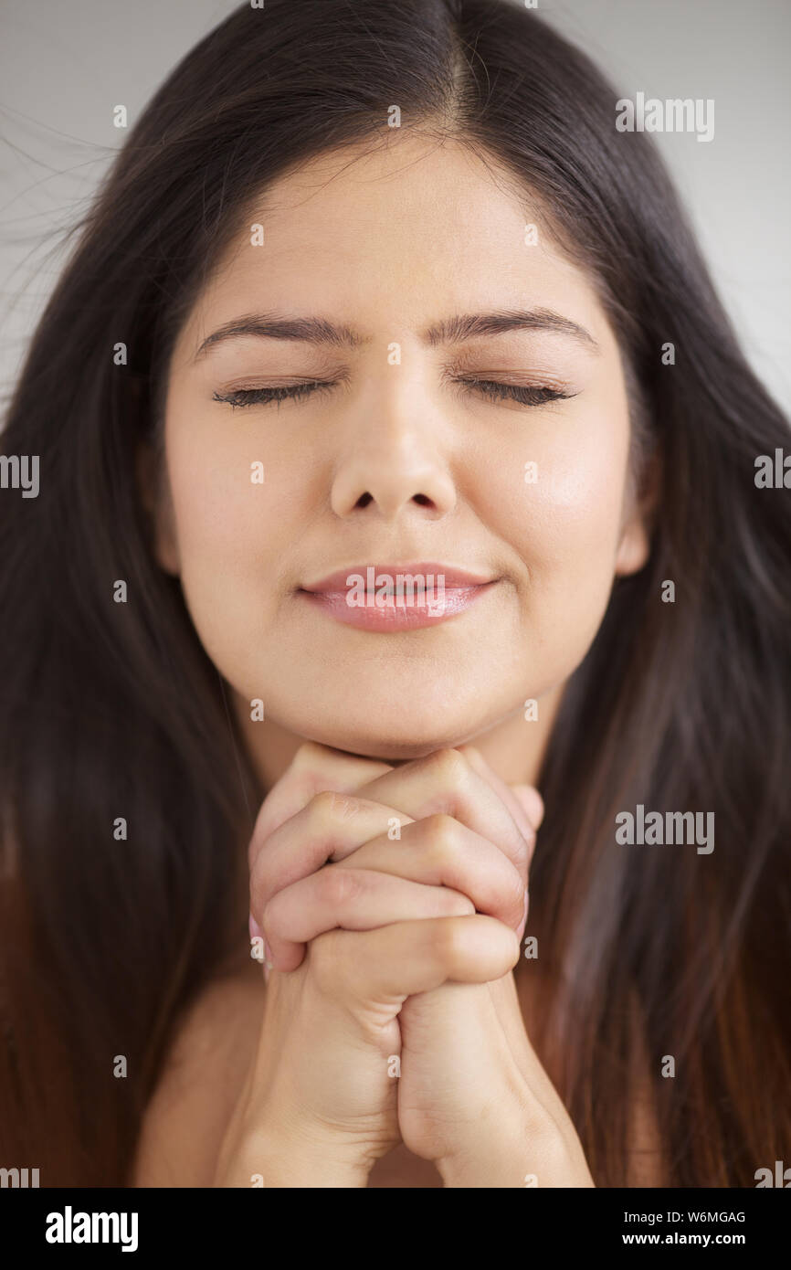 Woman wishing with clasped hands Stock Photo - Alamy