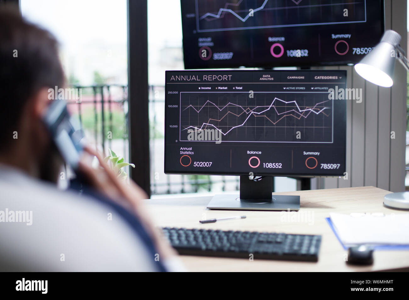 Back view of young business man talking on the phone sitting in his ...