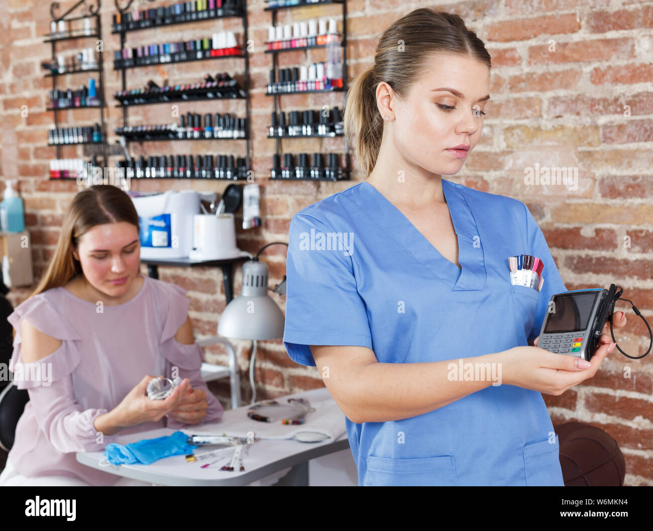Manicure salon worker girl helping to client with payments in salon ...