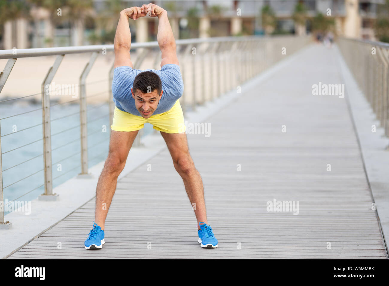 Positive male doing exercises on pier during morning workout Stock ...