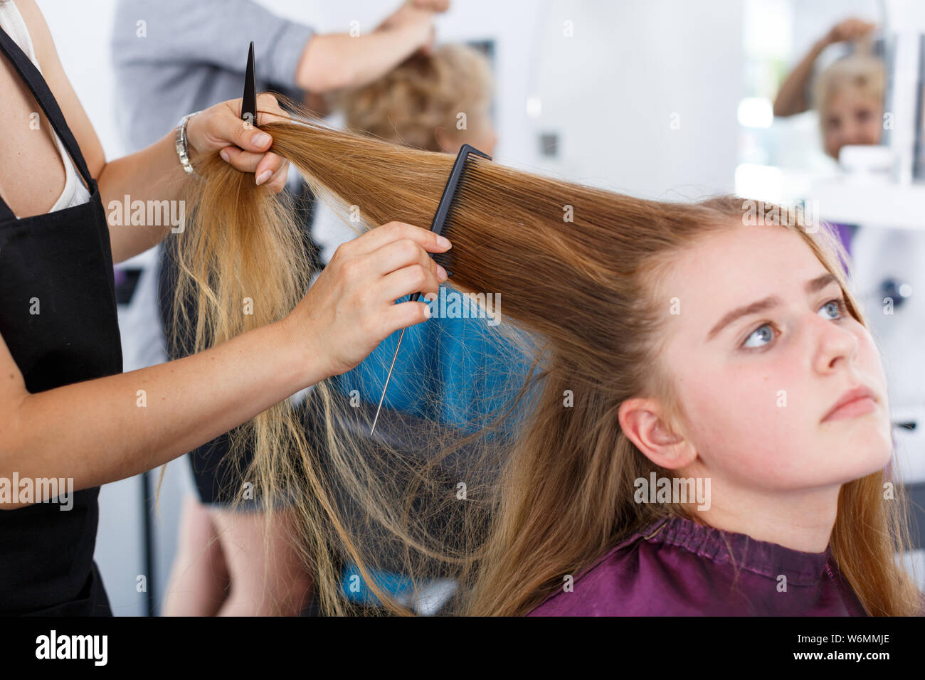 Closeup of long-haired teen girl getting haircutting by professional ...