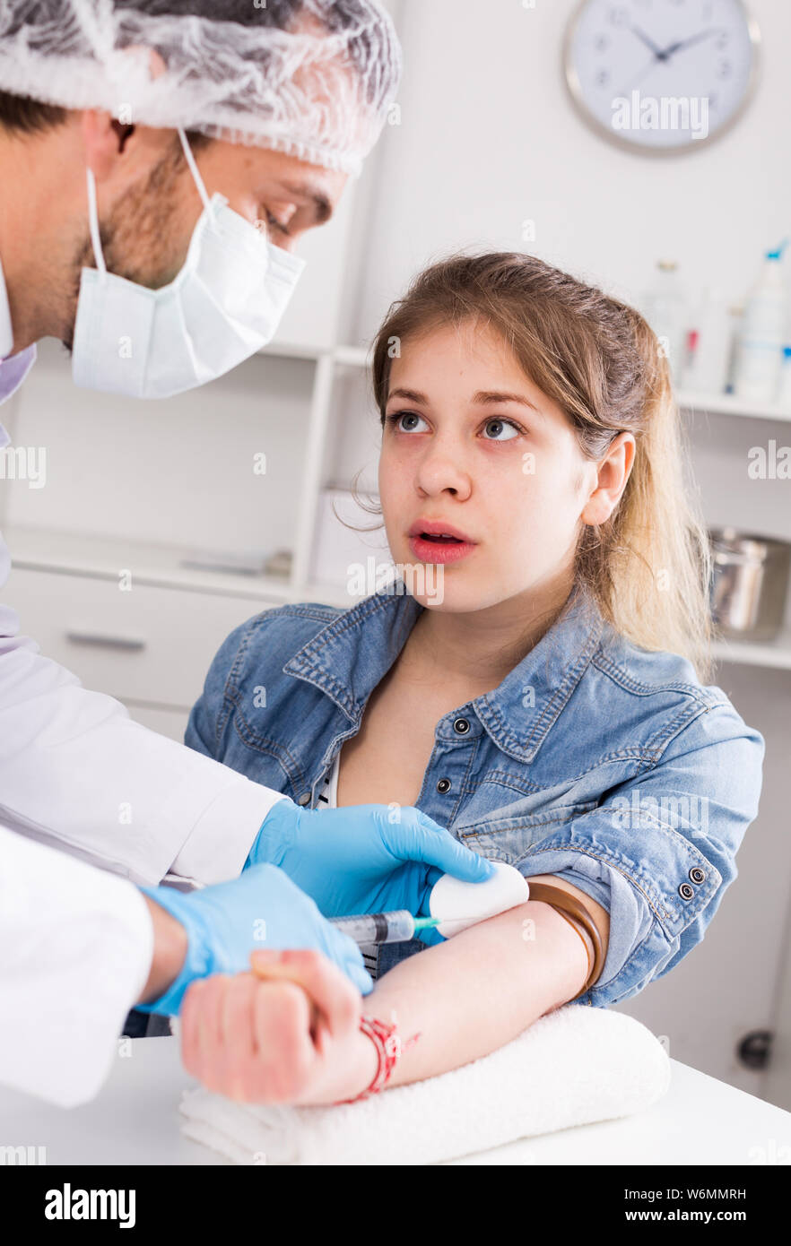 Male doctor using syringe to make injection to young patient in ...