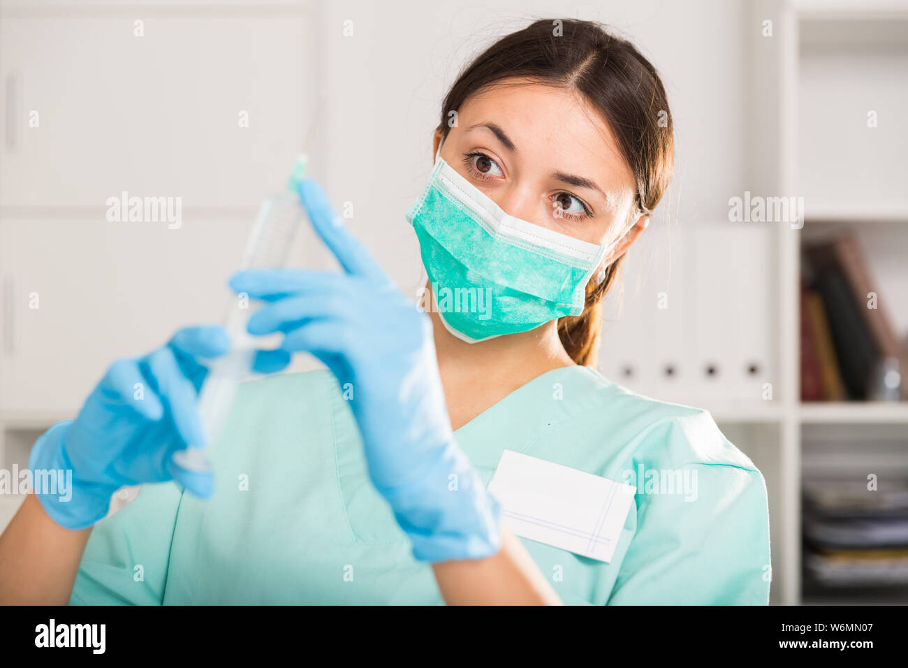 Young female nurse in mask holding syringe for injection in hospital ...
