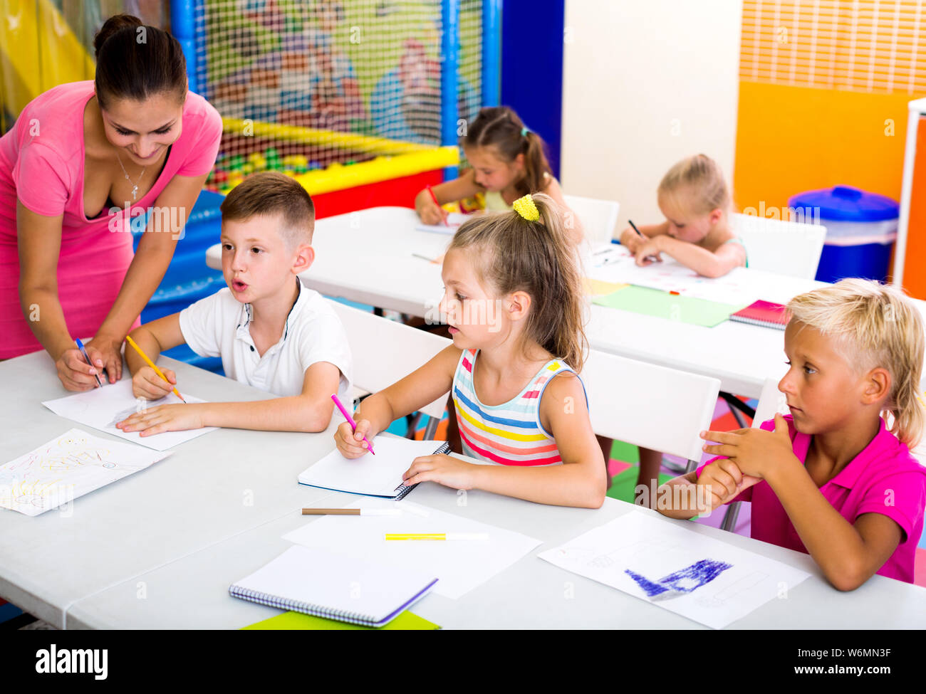 Smiling kids sitting and listening teacher in elementary school class ...