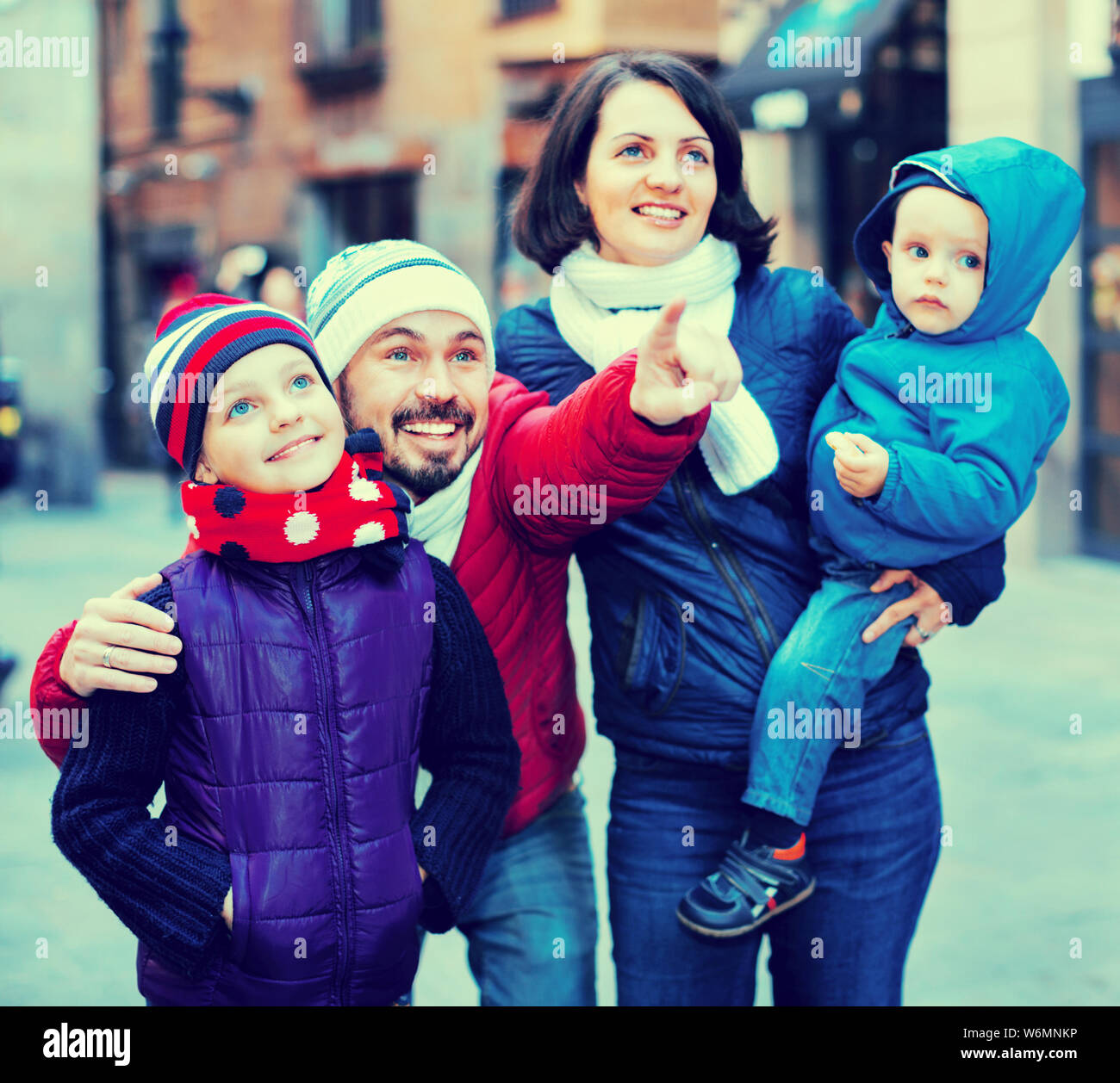 Happy smiling family of four walking in city and looking showplace at ...