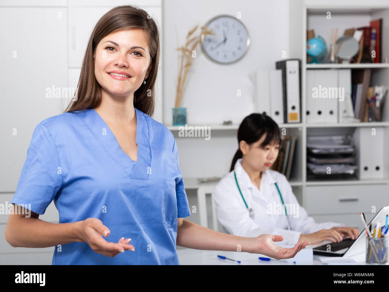 Portrait of young female doctor making welcome gesture welcoming ...