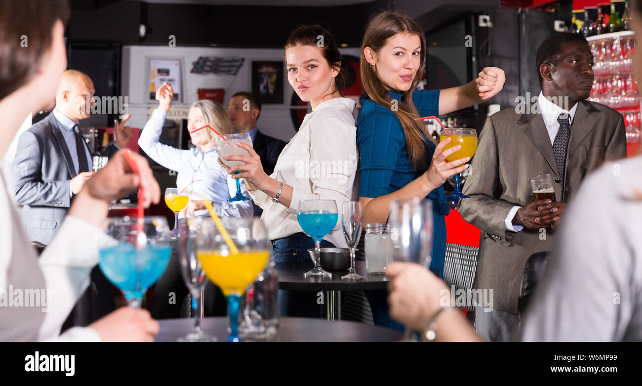 Young attractive women with cocktails having fun with workmates on ...