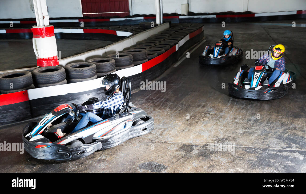 sportive positive man and women competing on racing cars at kart ...