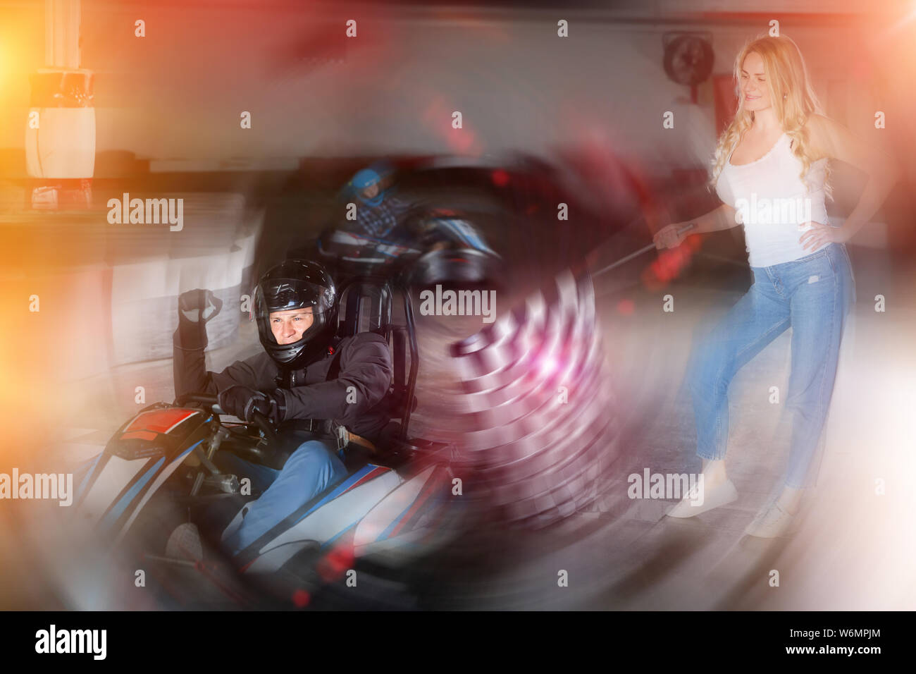 Fine woman with checkered race flag and man driving sport car for ...