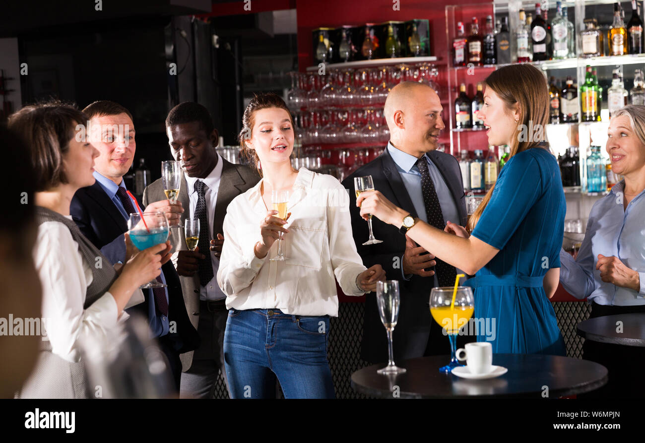 Two happy young women with colleagues enjoying corporate party in bar ...