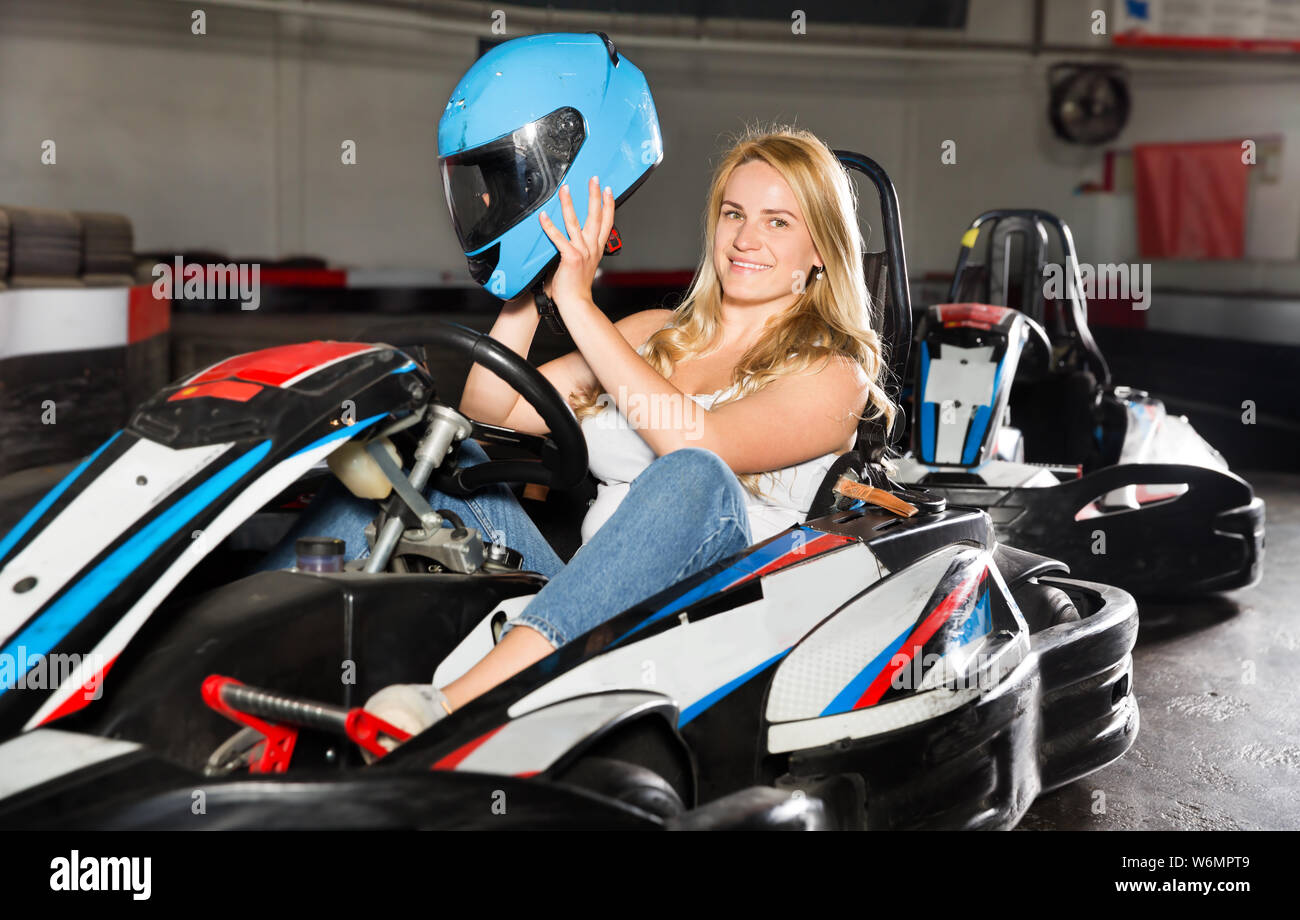 Portrait of female racer holding helmet in her hand on the kart track ...
