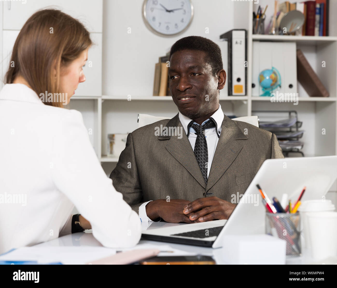 Positive business man working with female client at workplace in office ...