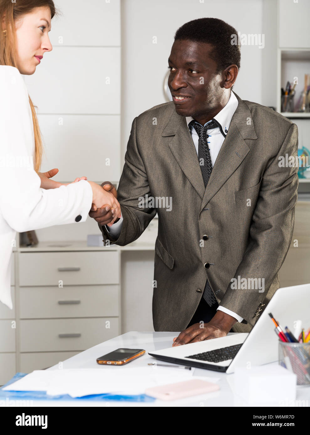 Successful African American businessman welcoming female client at ...