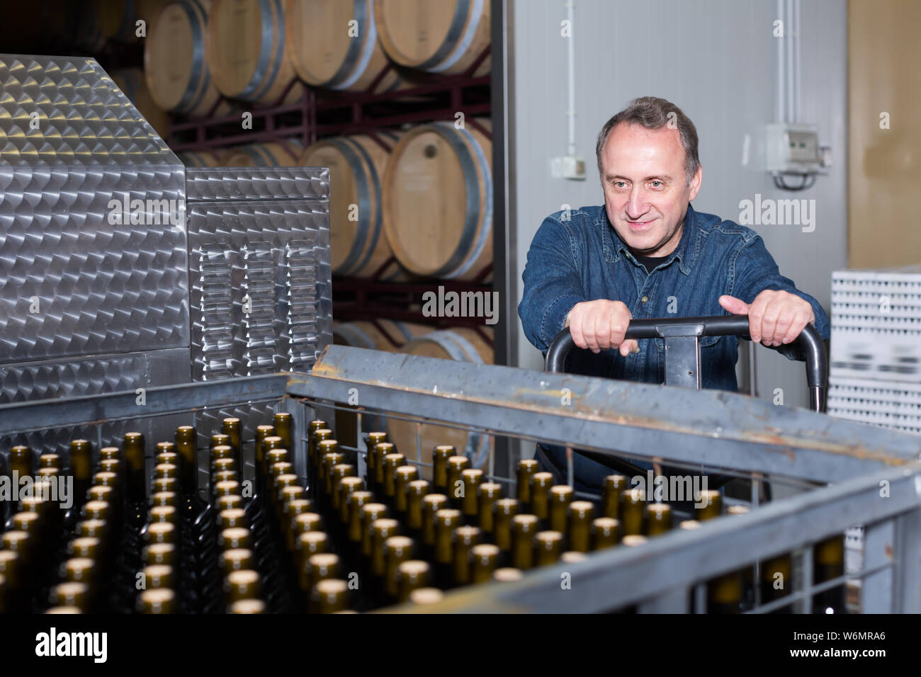 Adult wine maker unloads containers with bottles of red wine Stock ...