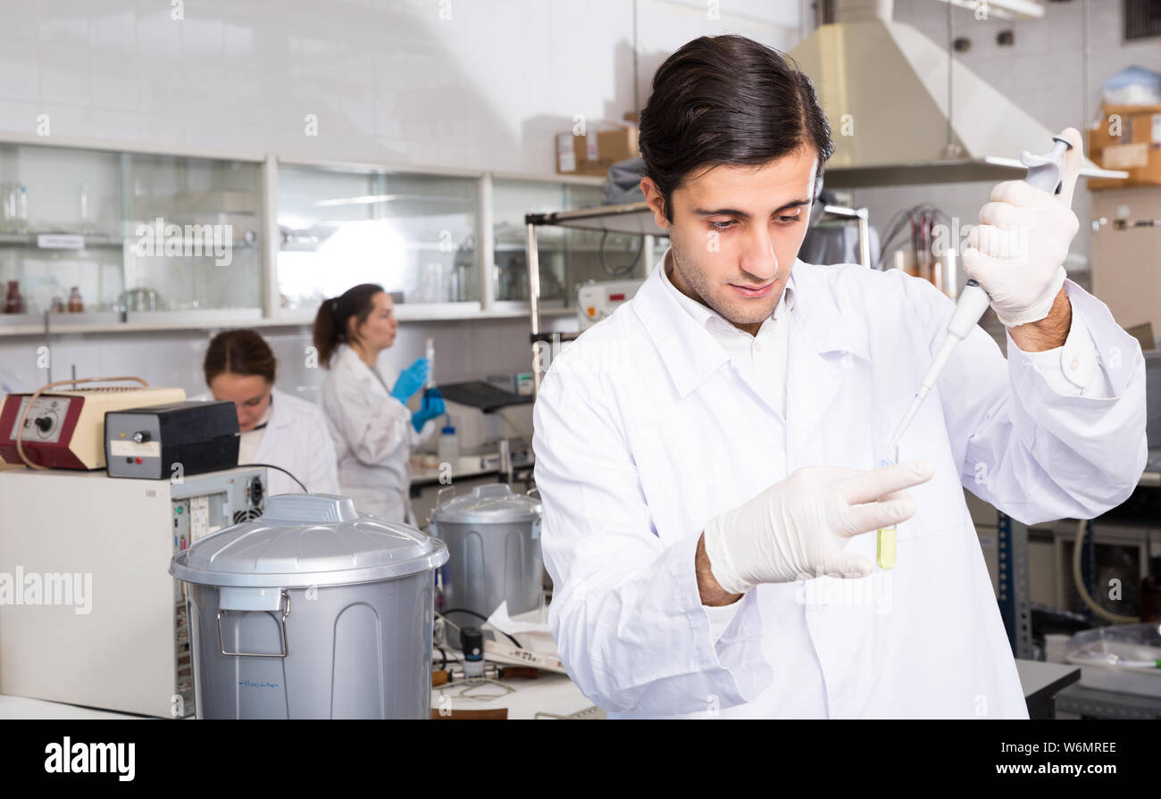 Professional chemist working in laboratory, mixing reagents in test ...