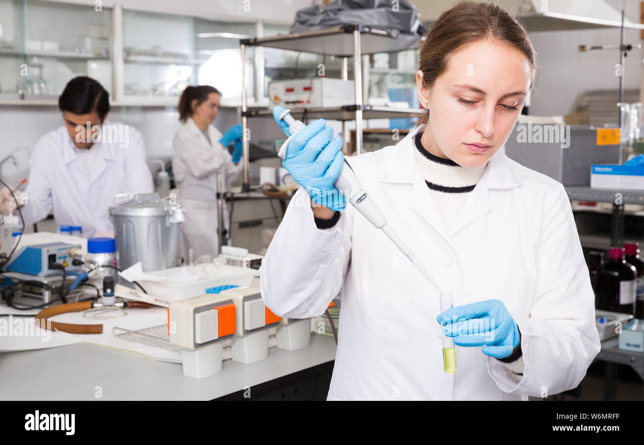 Professional female chemist working in laboratory, mixing reagents in ...