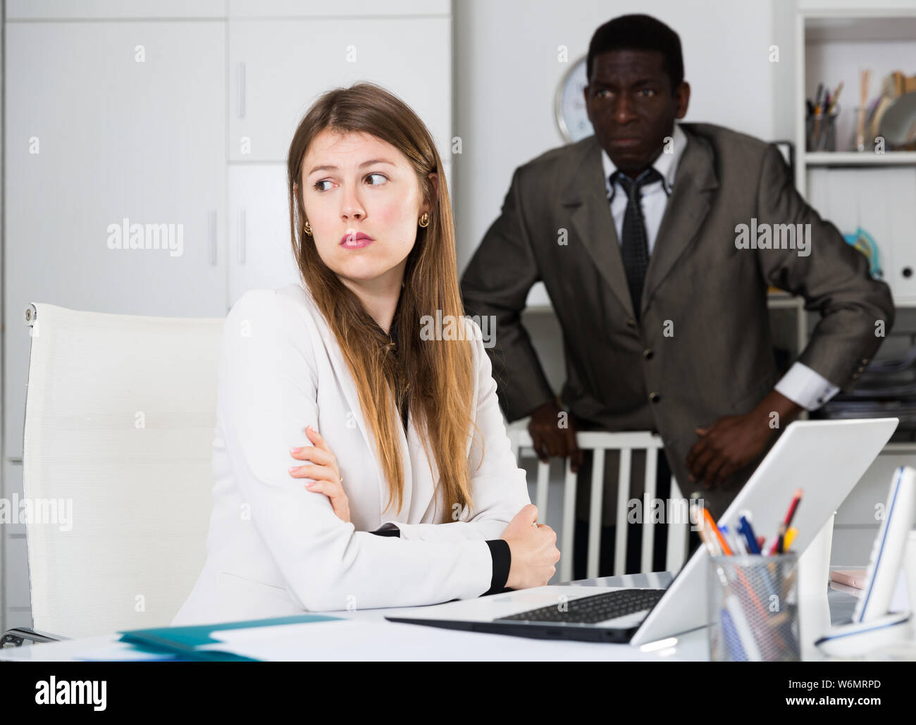 Young woman manager sitting at table after conflict, angry man boss on ...