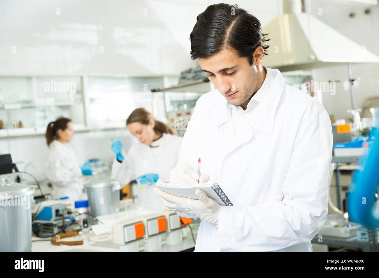 Young scientist engaged in research in chemical laboratory noting ...