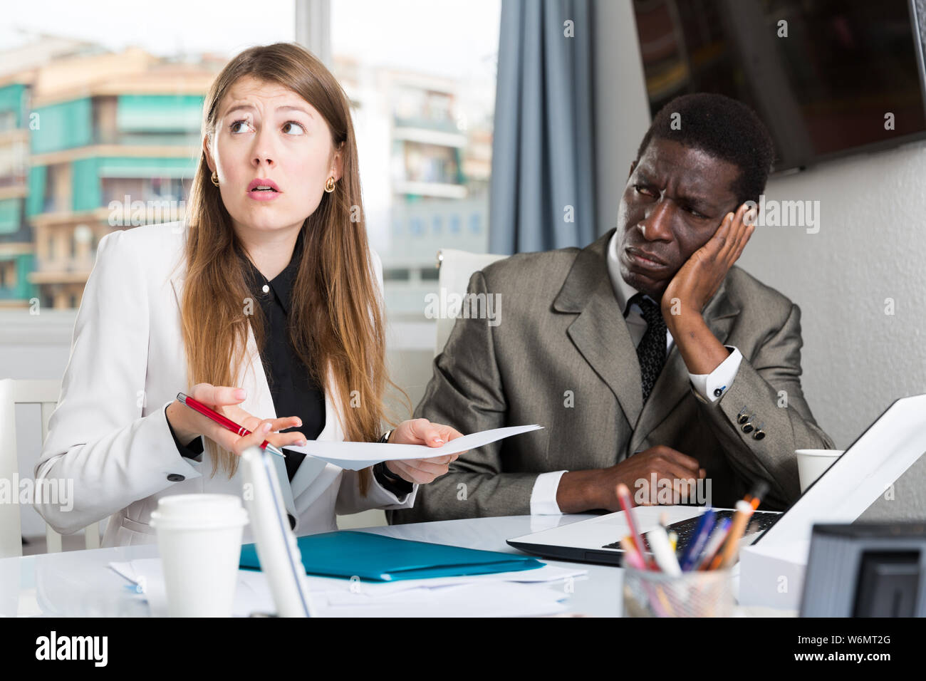 Frustrated business team working with papers and computer in modern ...