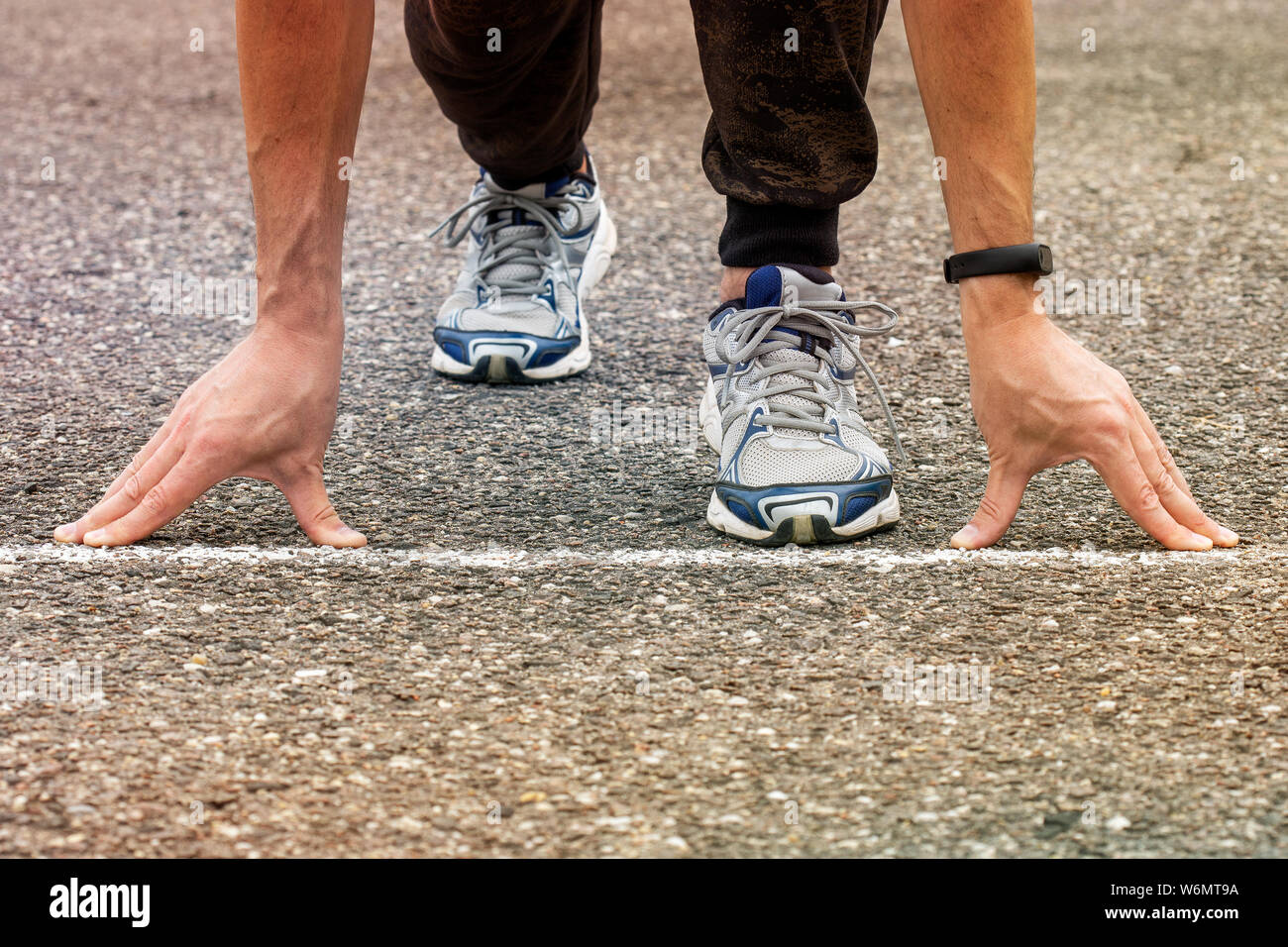 Runner in a stadium is in start position with hands on the line Stock ...