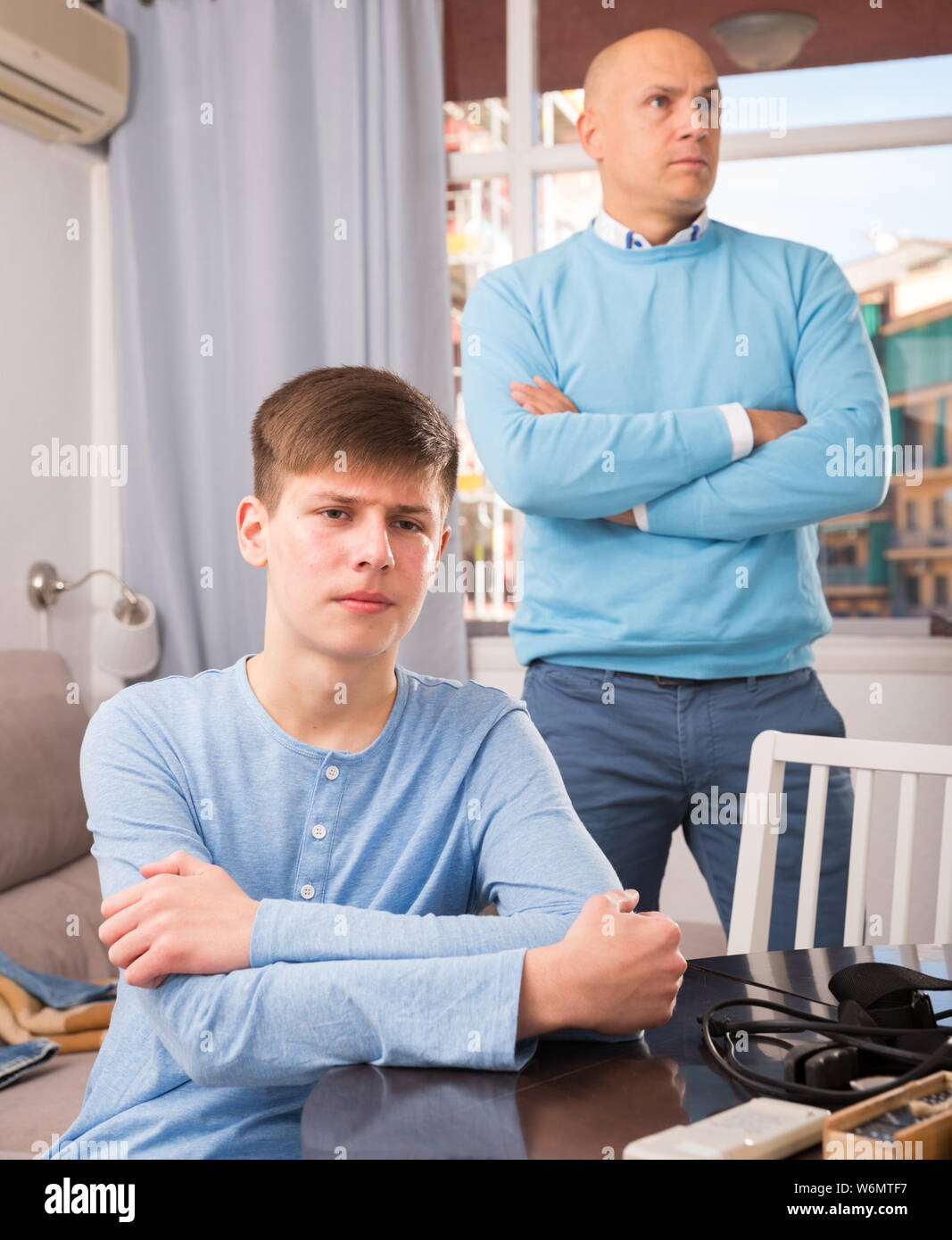 Frustrated boy sitting and looking away after quarrel with annoyed ...