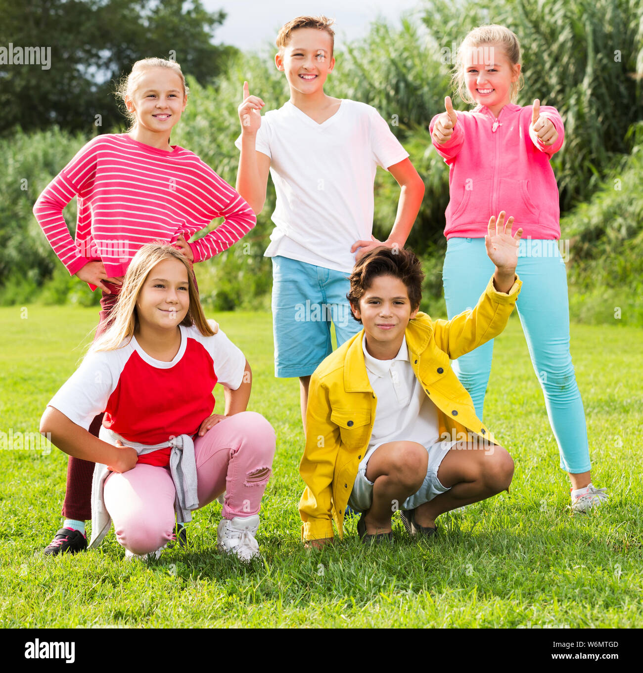 Portrait of five glad children who are walking and posing in the park ...