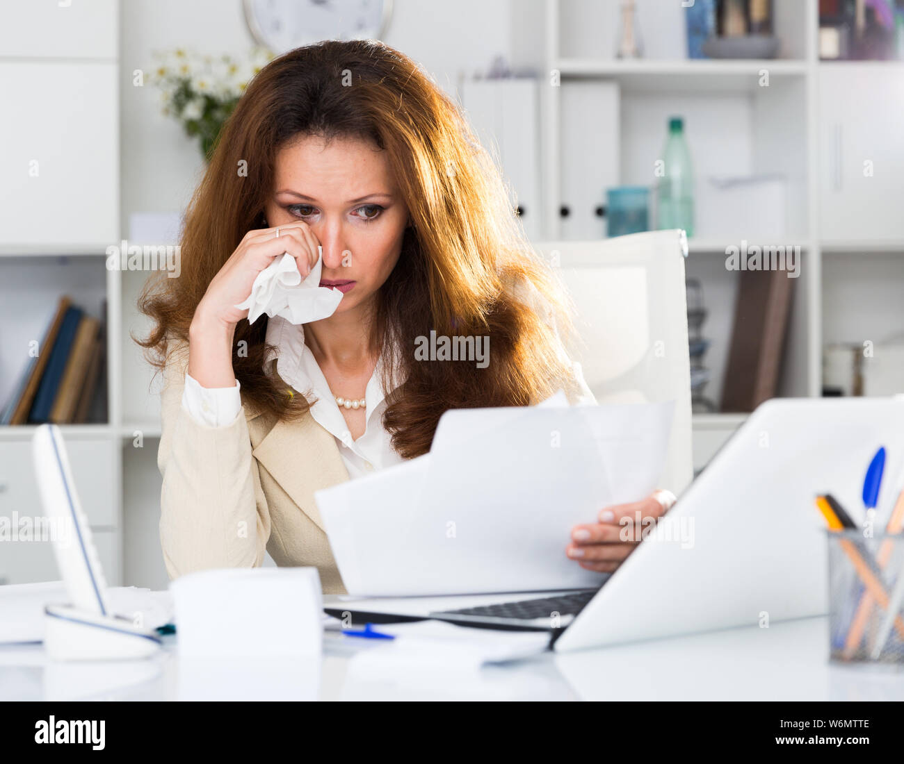 Adult woman is crying because of problems with documents in the office ...