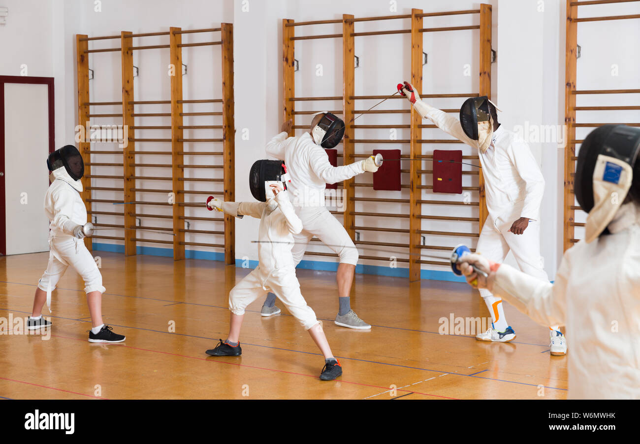 Happy group practicing effective fencing techniques in sparring in ...