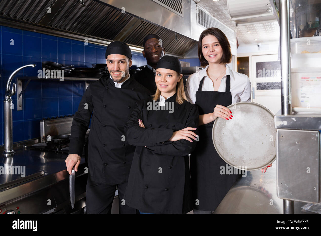 Portrait of command of cooks and woman waiter who are posing together ...