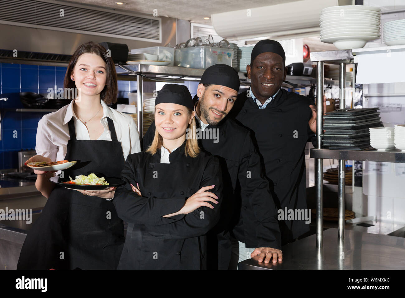 Portrait of command of cooks and woman waiter who are posing together ...