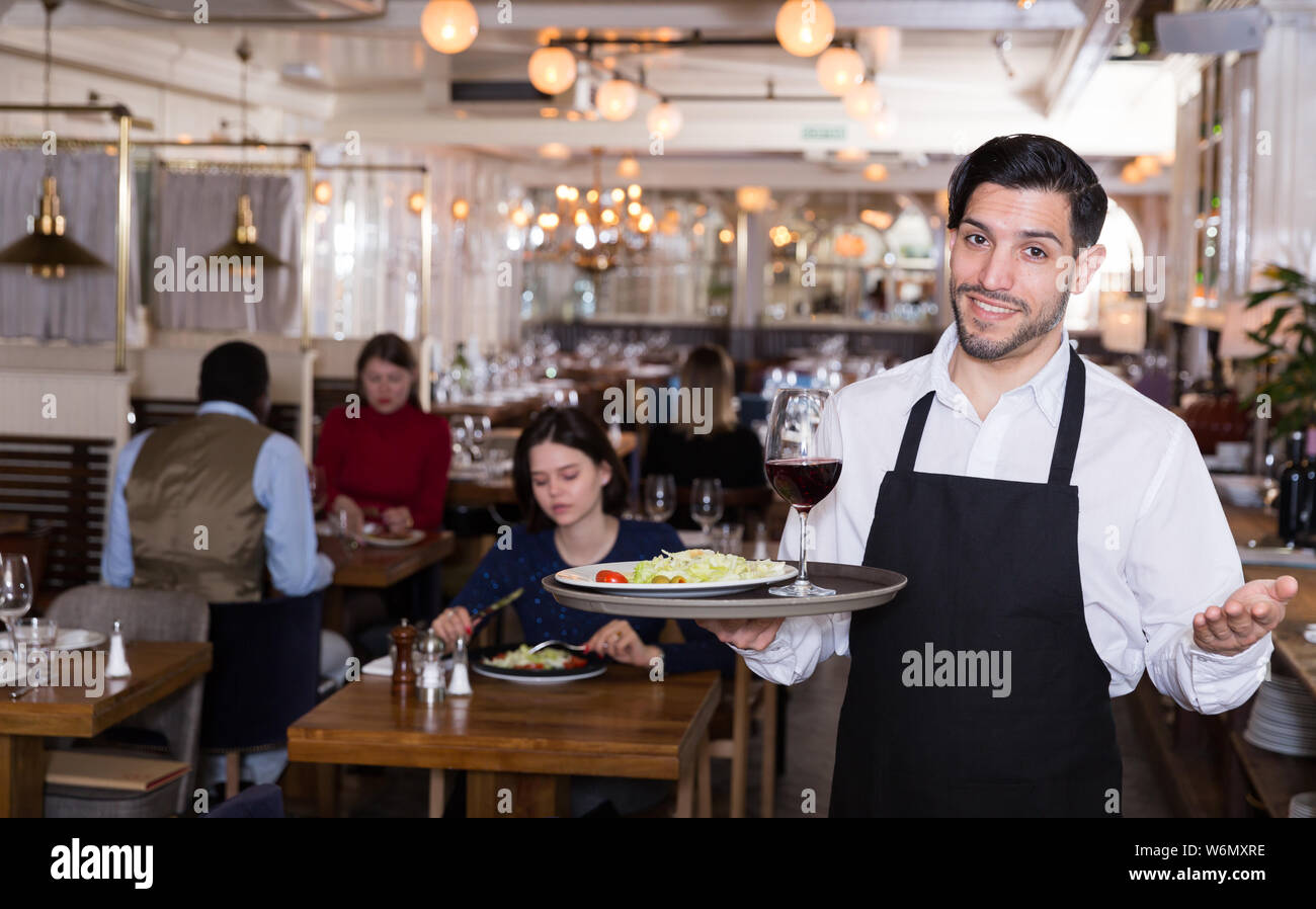 Man waiter is standing with order in hall of luxurious restaurant Stock ...