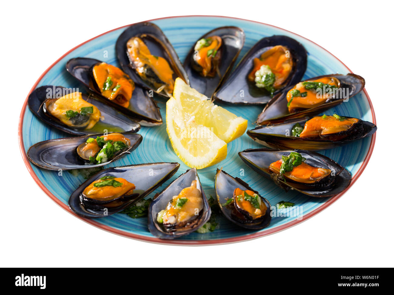 Gourmet steamed mussels with garlic herb sauce and lemon served on blue ...