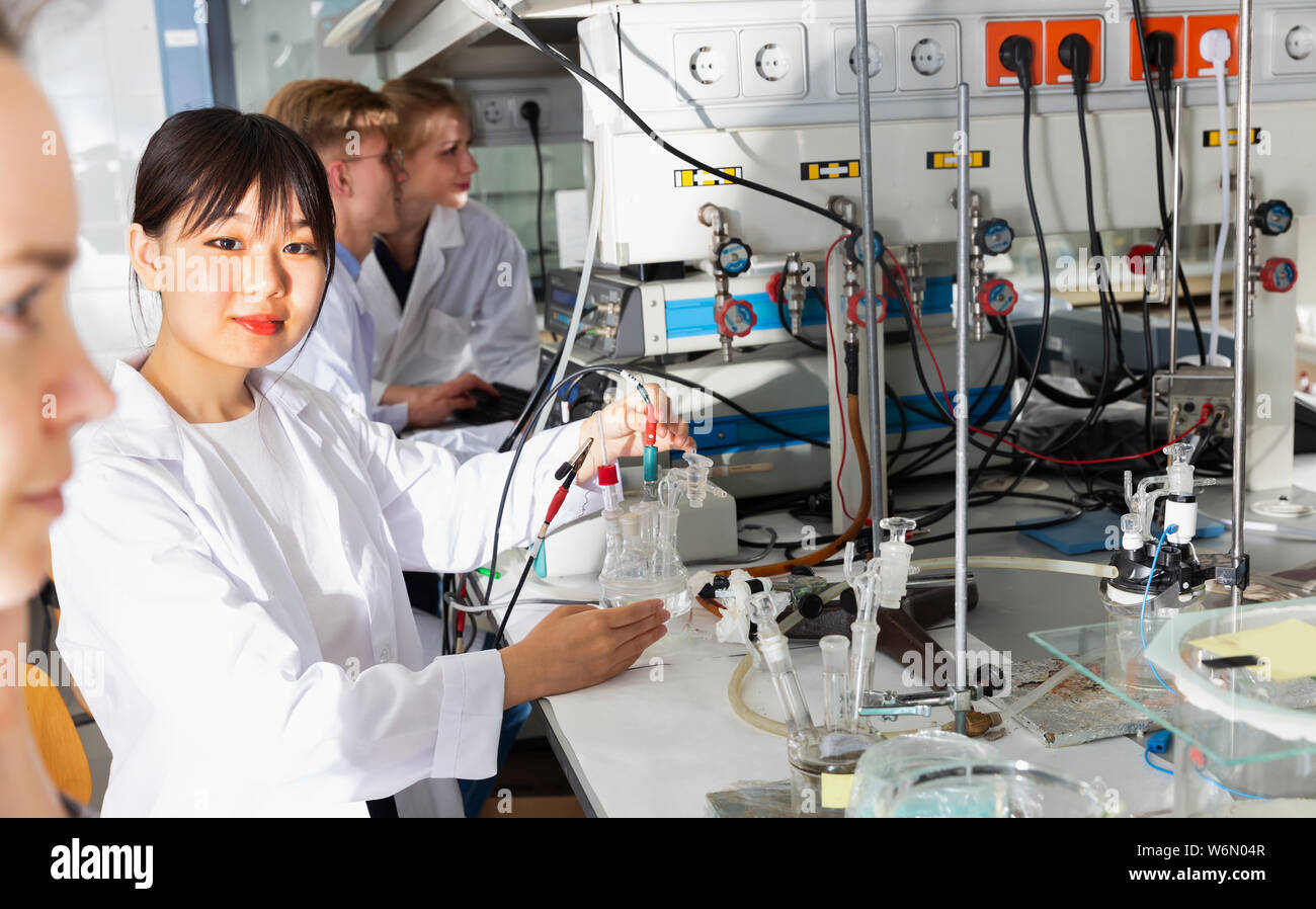 portrait of intelligent Chinese girl working with reagents in test ...