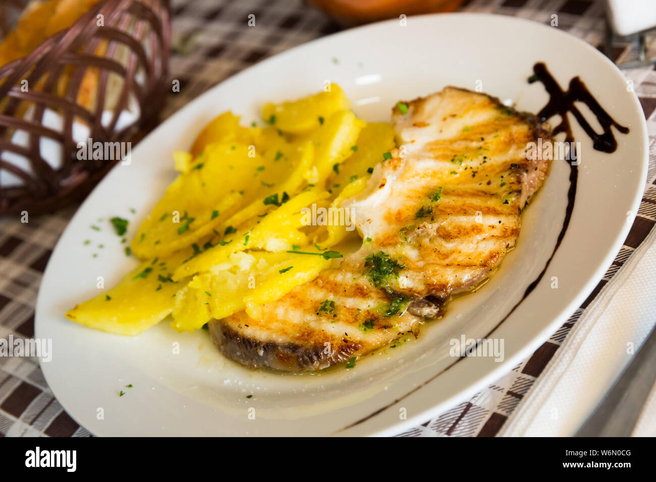 Roasted shark steak served with baked potatoes and traditional Spanish ...