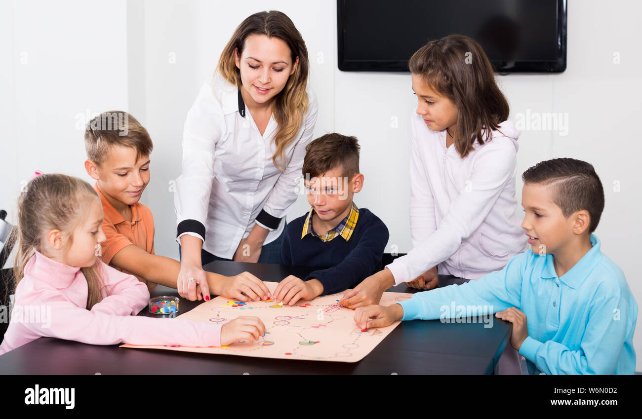 Happy children sitting at table with board game and dice Stock Photo ...