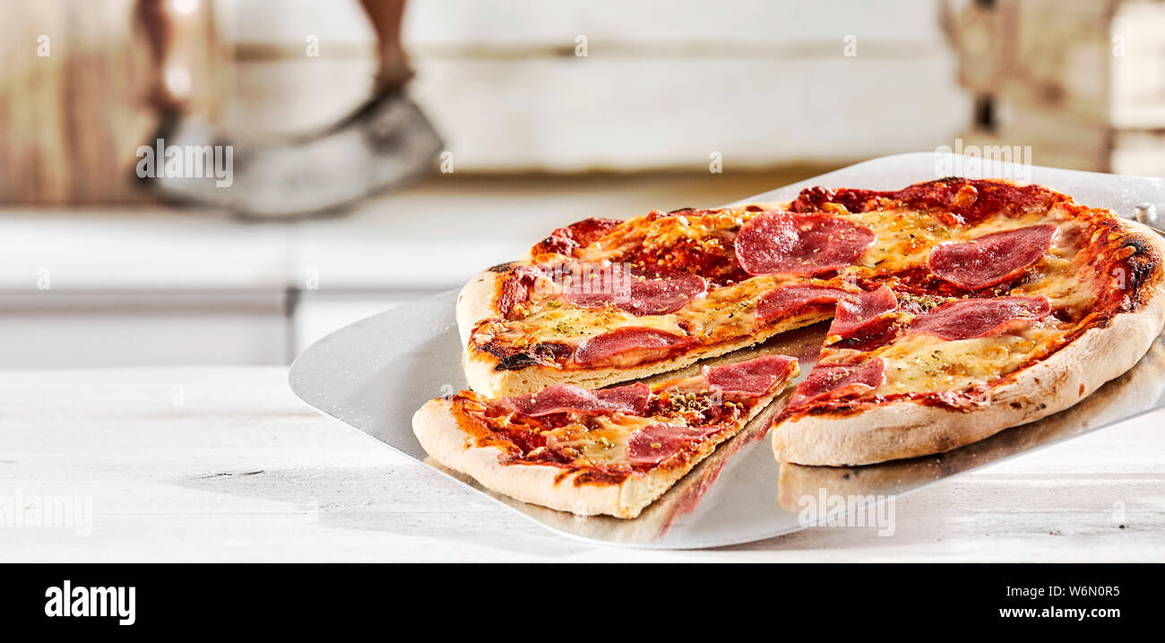 Freshly prepared Italian salami pizza served on a metal paddle in a ...
