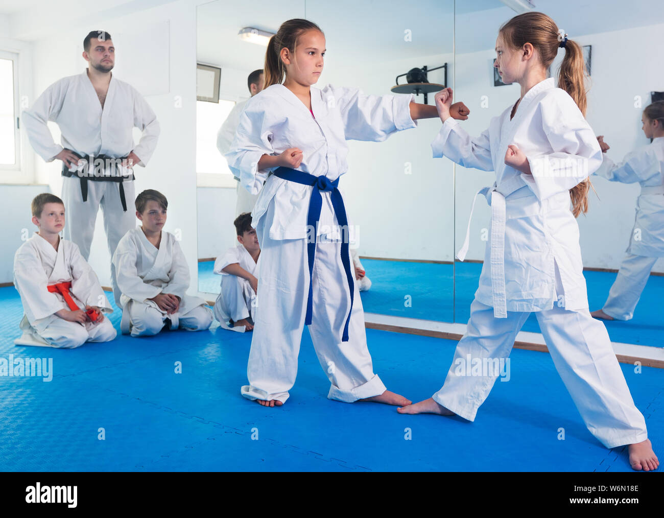 Young girls practicing in pair to use new techniques during karate ...