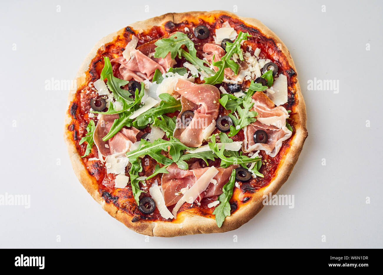 Tasty gourmet Italian pizza with prosciutto, black olives, parmesan ...