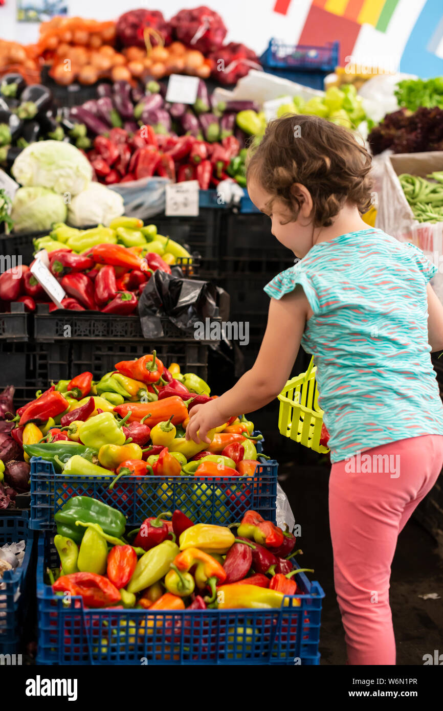 Kid shopping in vegetable market. Child collect peppers in basket Stock ...
