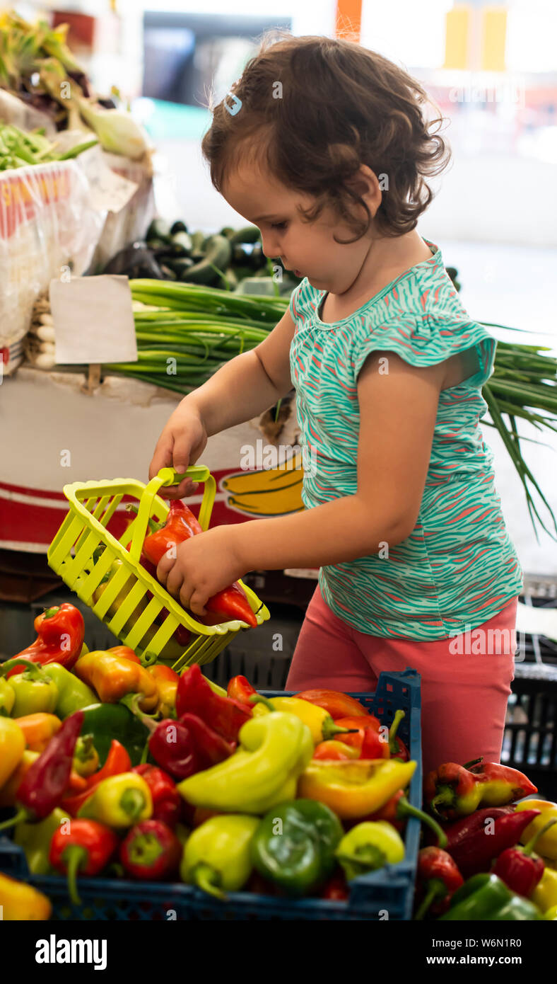 Kid shopping in vegetable market. Child collect peppers in basket Stock ...