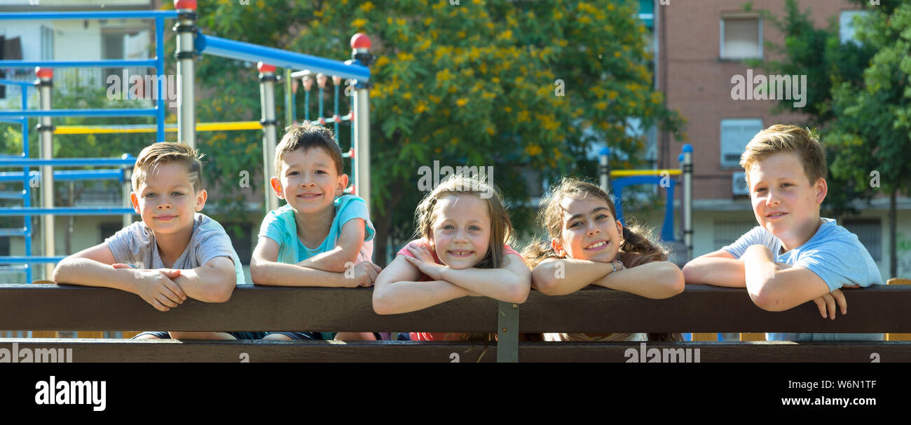 Five glad children sitting on a bench at the playground Stock Photo - Alamy