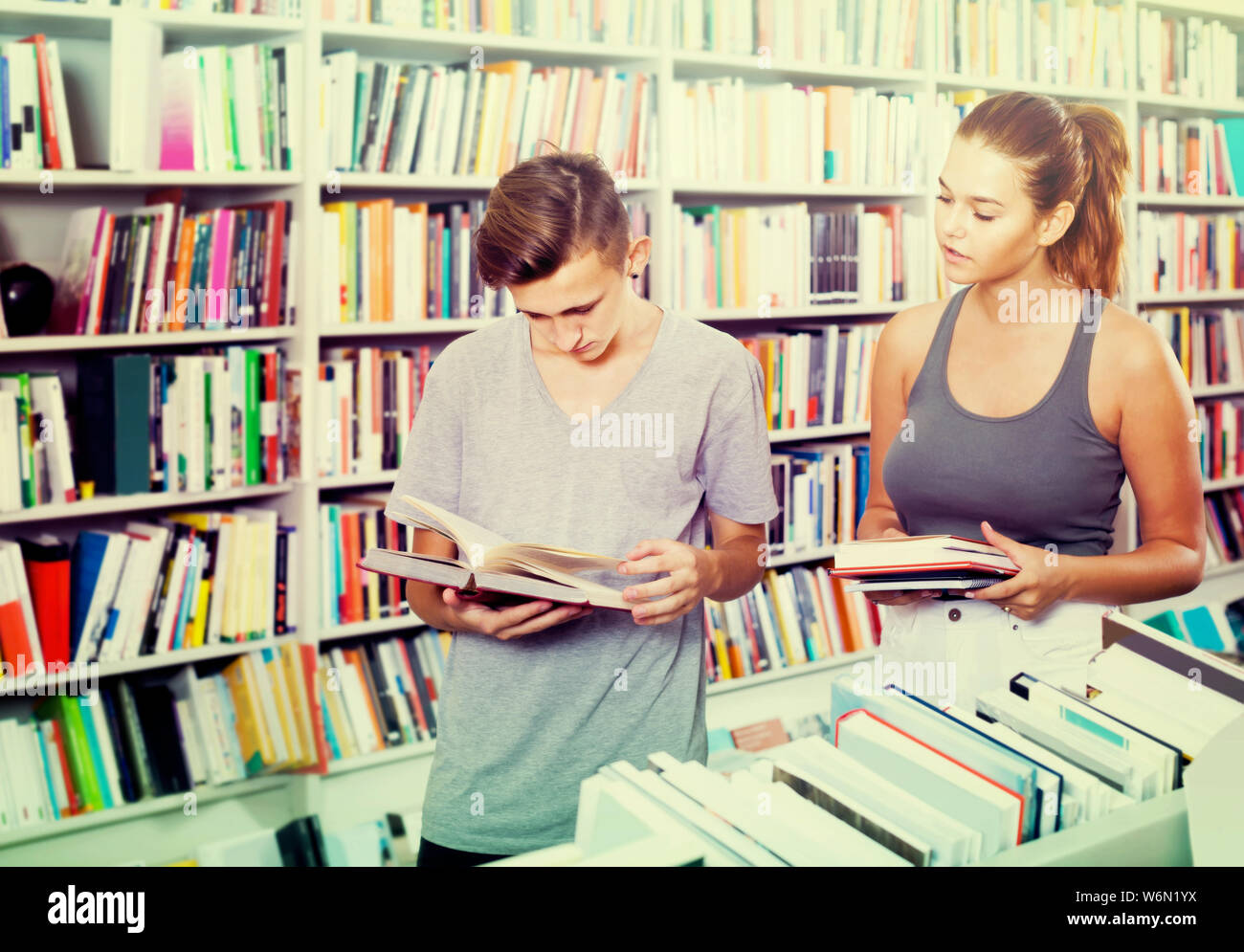 portrait of positive european teenage boy and girl customers looking at ...